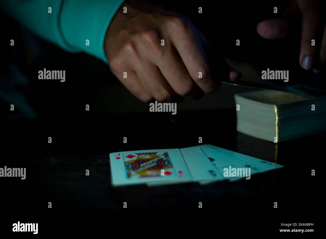 A man playing with cards on a table in a dark background Stock Photo ...