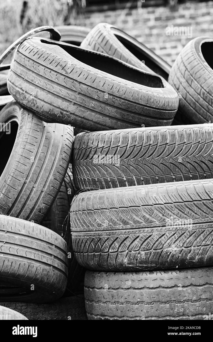 A vertical grayscale shot of many used old car tires Stock Photo - Alamy