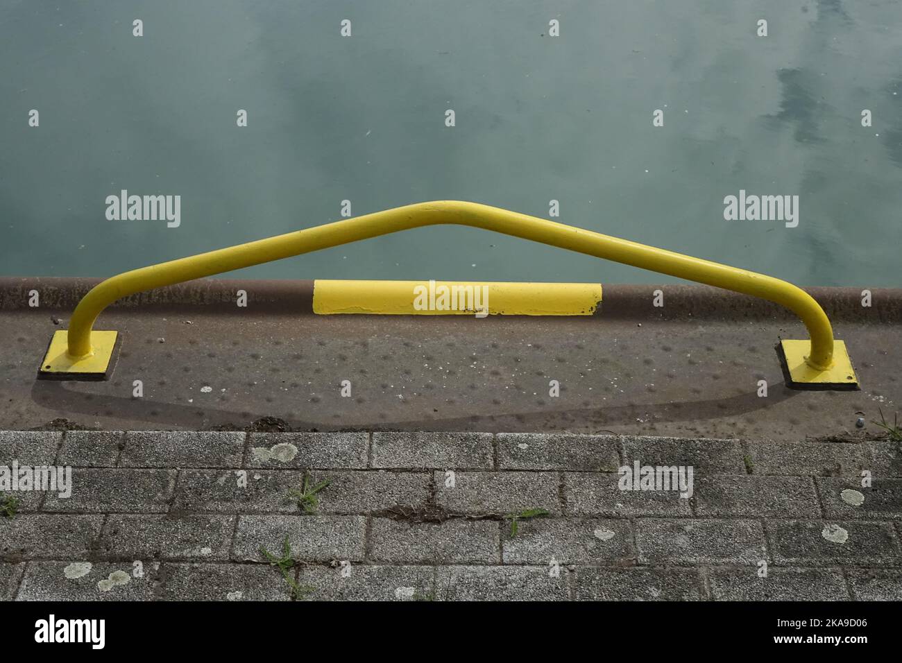Yellow bollard, iron wall and paving at the dock of Hildesheim Harbour ...