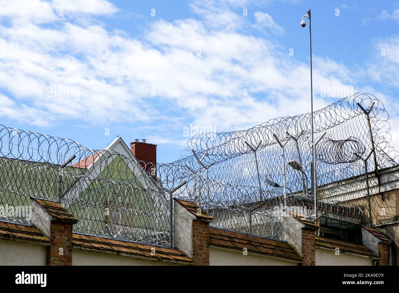 Lots of barbed wire over a brick fence around the perimeter of the ...