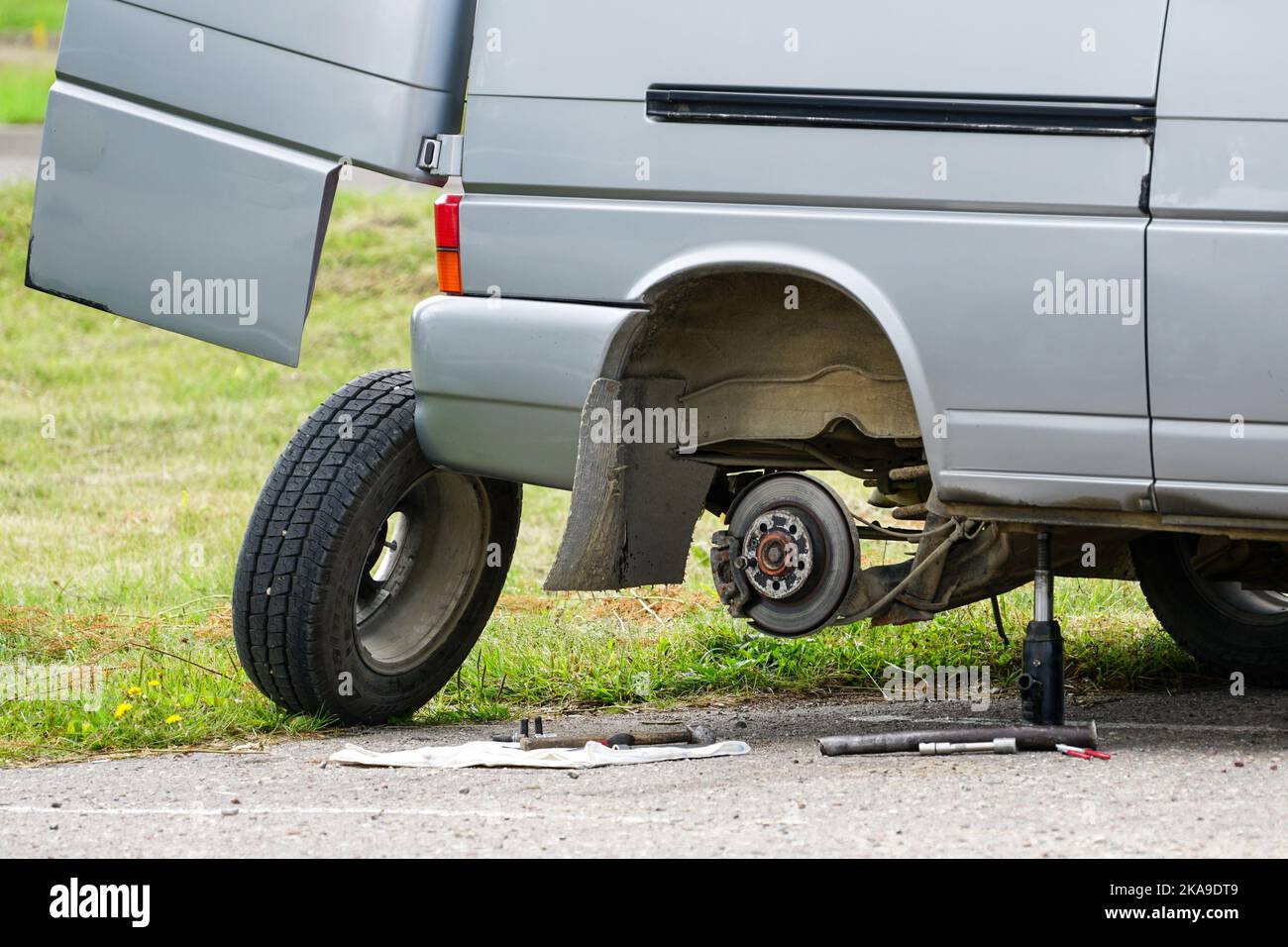 Minibus with rear wheel removed, lifted by hydraulic jack, car repair ...