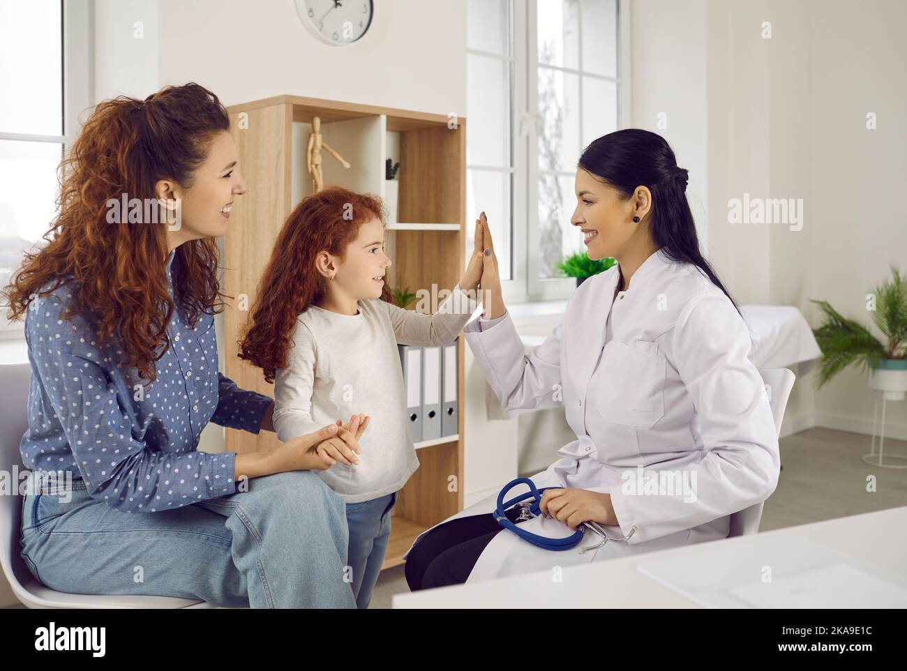 Happy kid and caring doctor give high five Stock Photo - Alamy