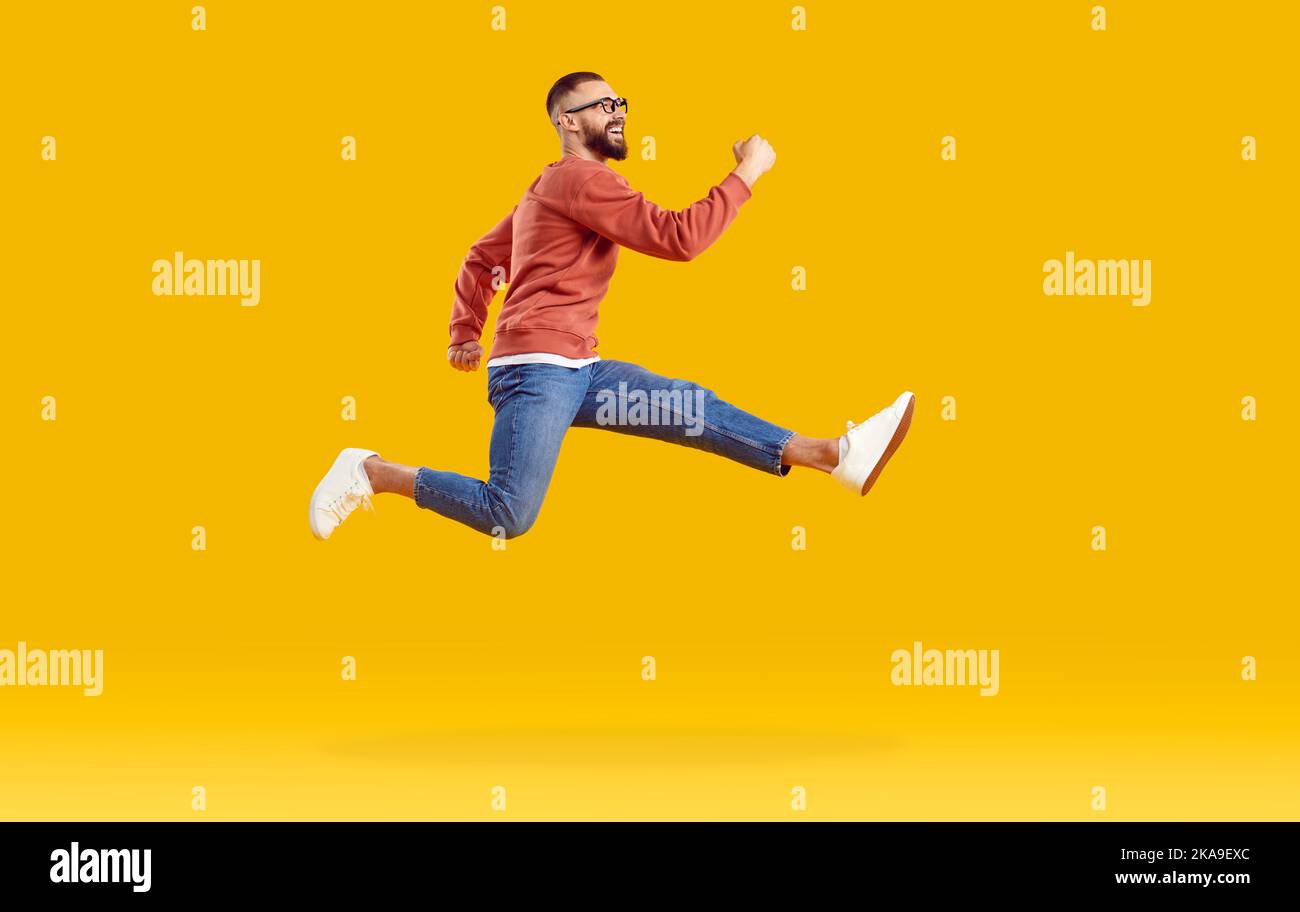 Cheerful joyful man running funny to crazy discount, isolated on orange ...