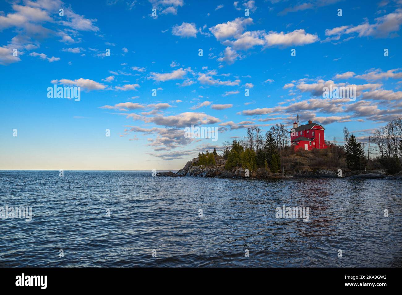This red lighthouse stands as a beacon in a seascape draped in shades ...