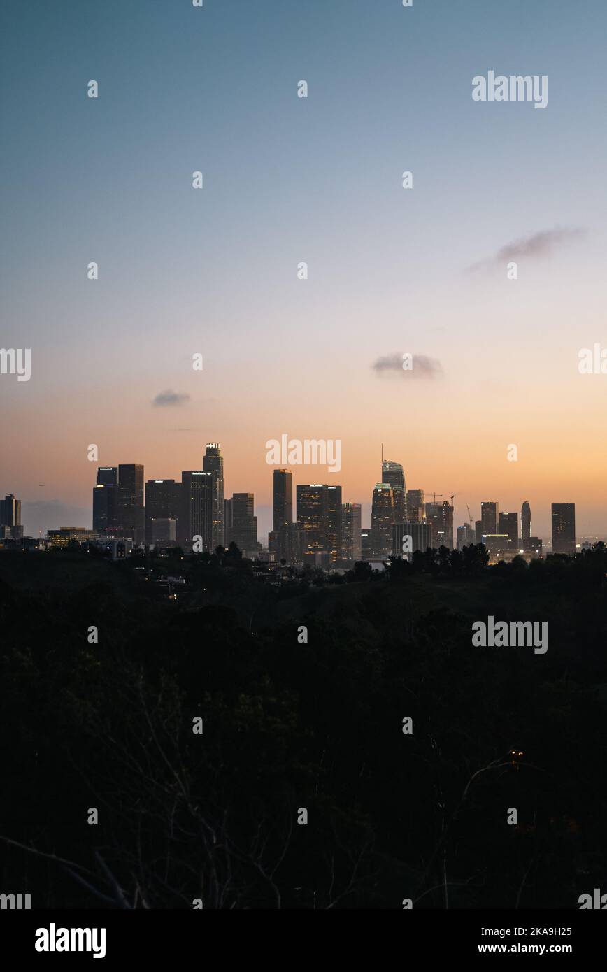 A vertical view of a city skyline of modern buildings on a sunset sky ...