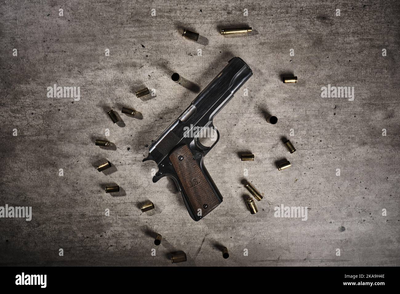 A top view of a pistol handgun with bullets around it on a stone ...