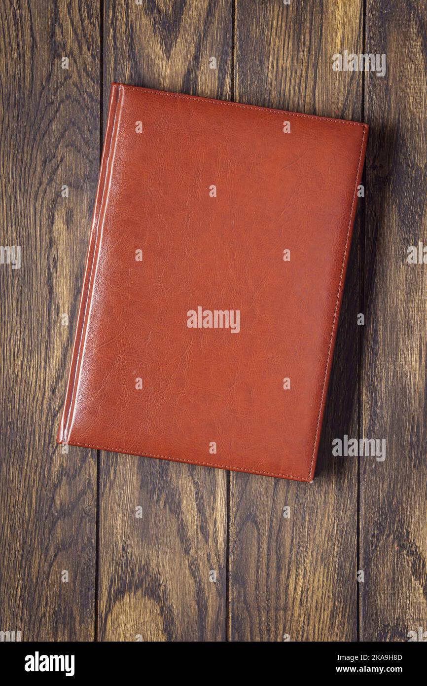 Red leather-bound book on wooden oak table as a template layout Stock ...
