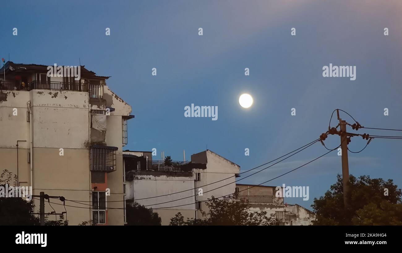 A beautiful view of the full moon above the city Stock Photo - Alamy