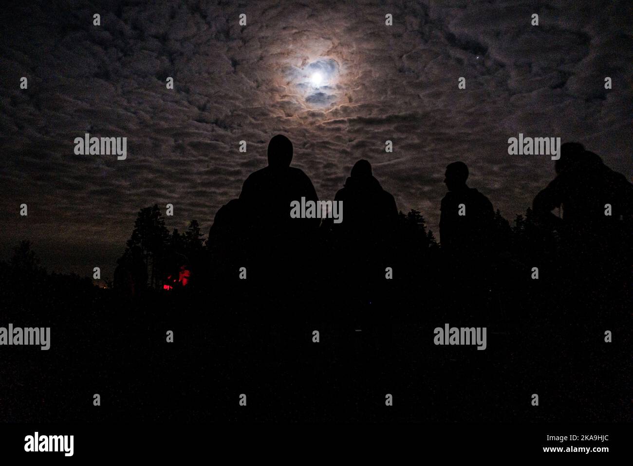 A scenic view of a group of people against cloudy night sky background ...