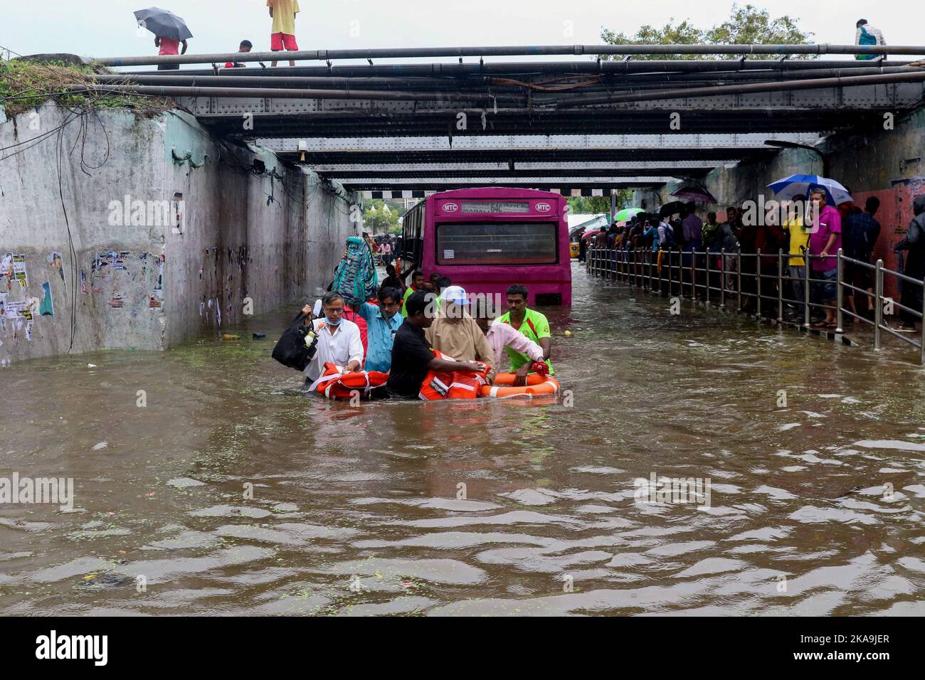Chennai, India. 1st Nov, 2022. People wade through a waterlogged street as a passenger bus broke ...