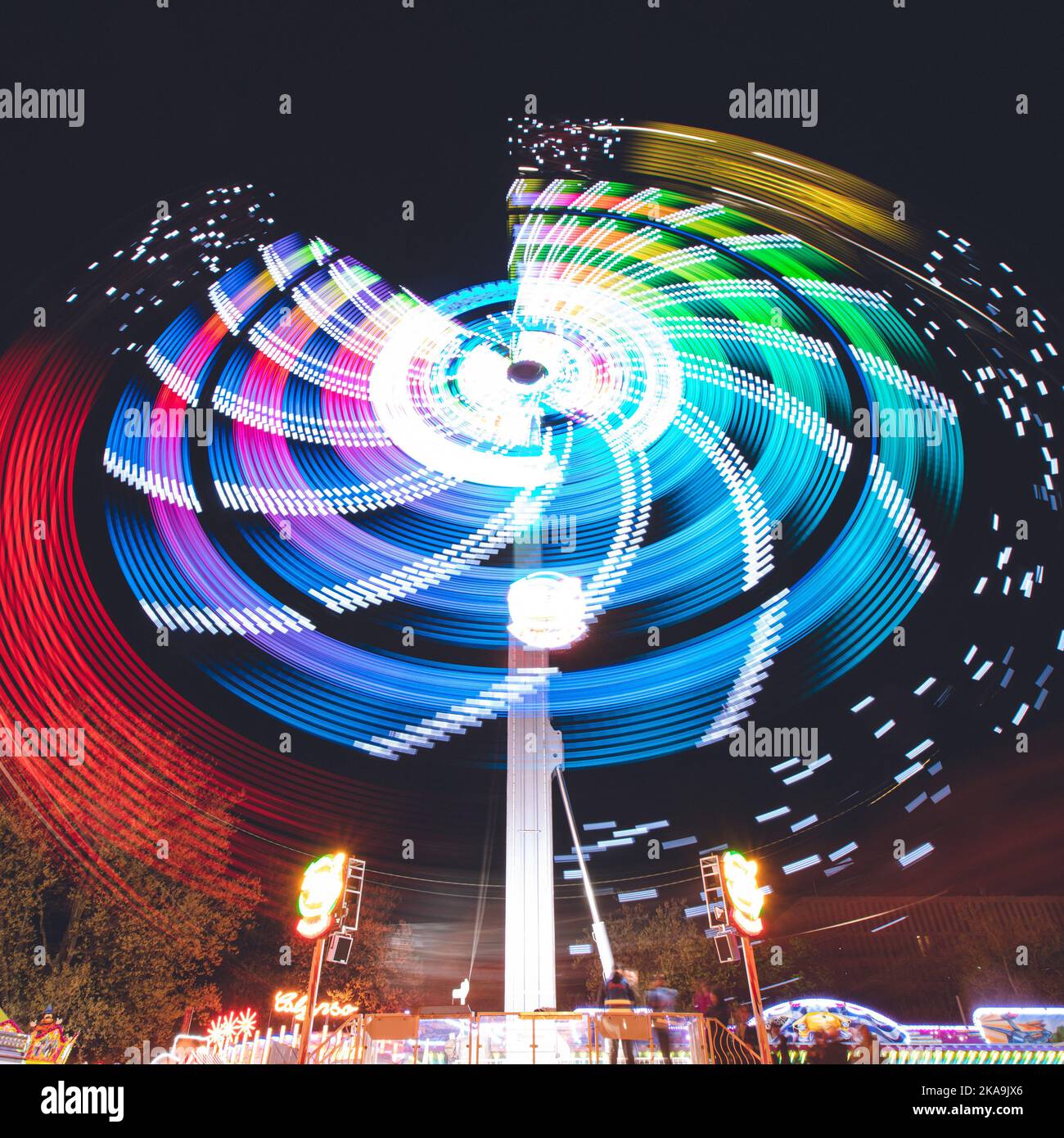 A low angle of a rotationg colorful Ferris wheel in an amusement park ...