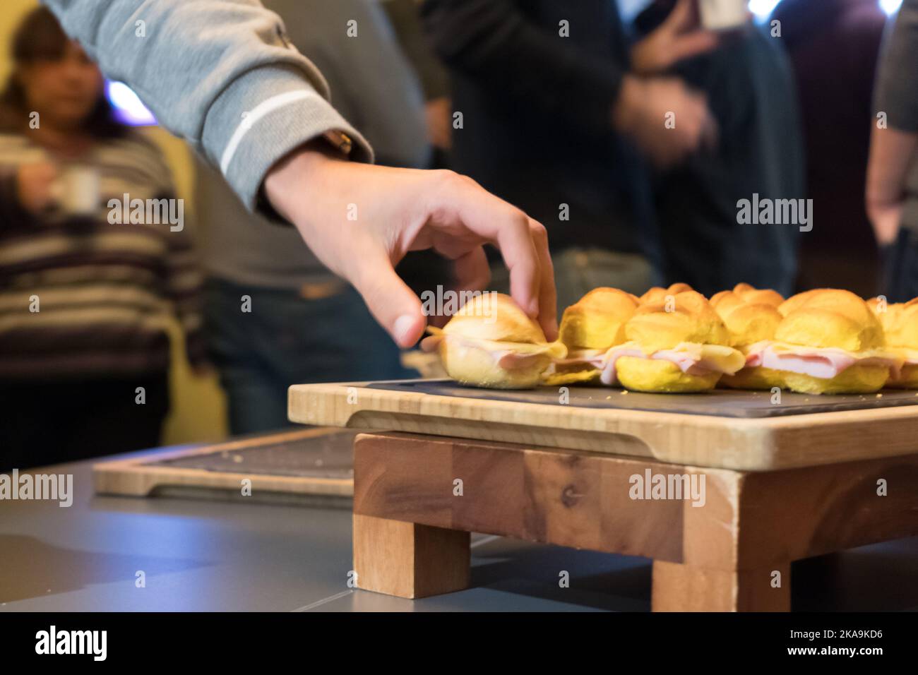 hand of a person taking a mini sandwich on a buffet table during a ...