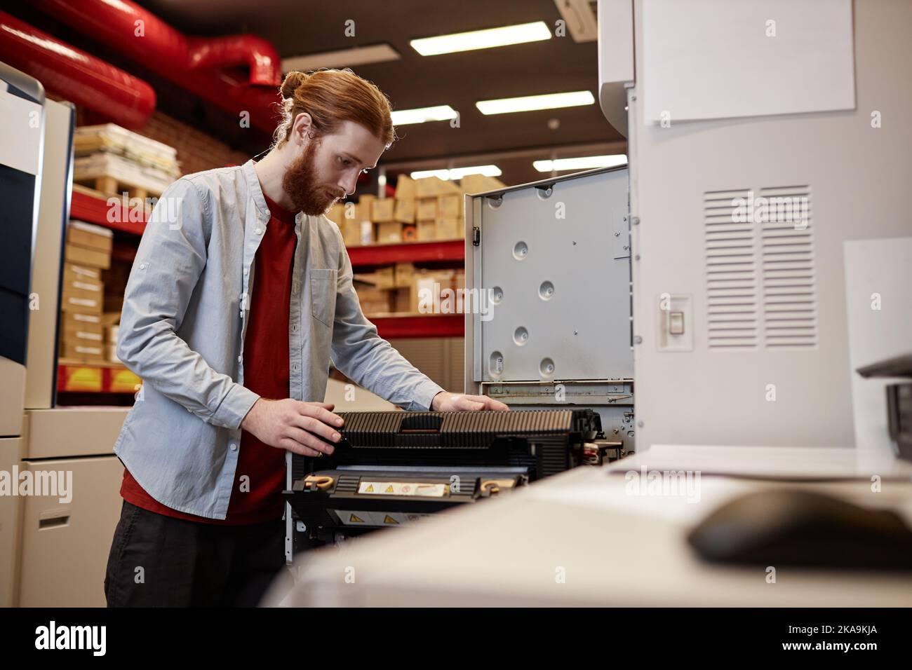 Side view portrait of red haired young man operating printing machine ...