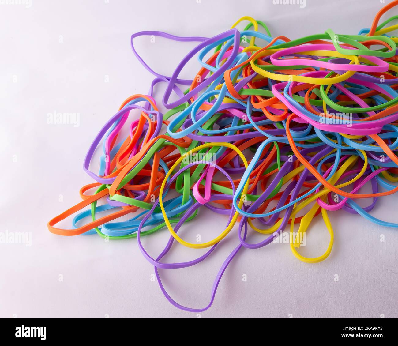A pile of neon multi-color rainbow rubber bands on white background ...
