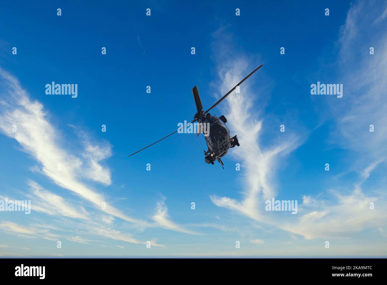 flying helicopter in blue cloudy sky, front view, from below Stock ...