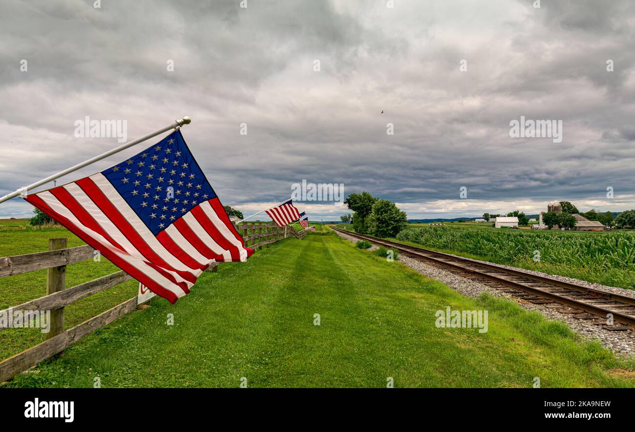 On a Cloudy Day American Flags are Waving in the Wind, on a Fence near ...