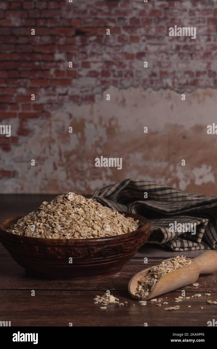 oat flakes in a wooden bowl with a kitchen towel on a wooden table and ...