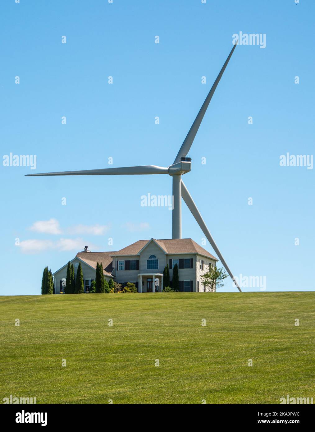A beautiful house in green landscape with huge wind mill in the back ...