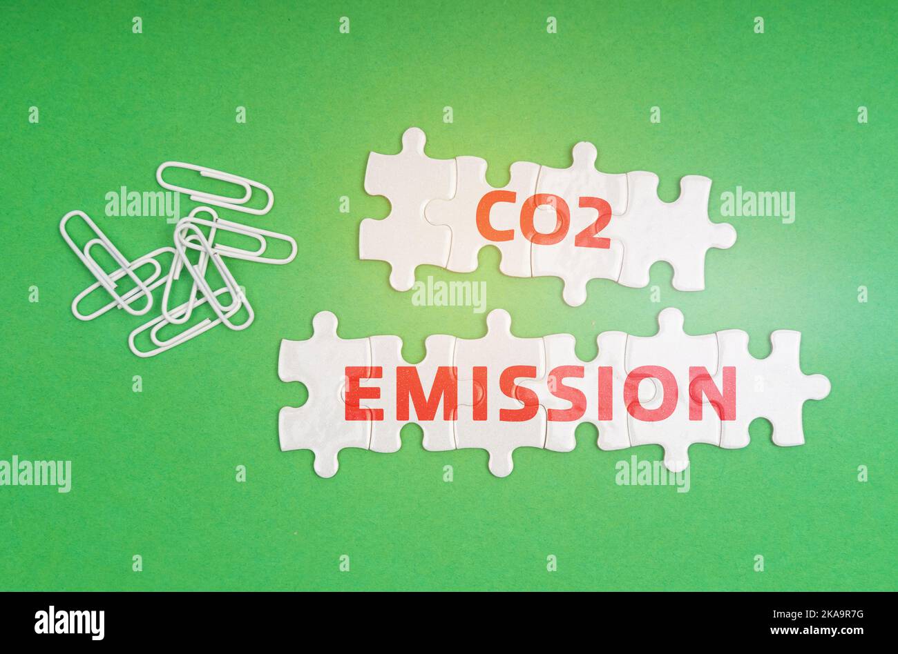 Ecology concept. On a green background, paper clips and white puzzles ...