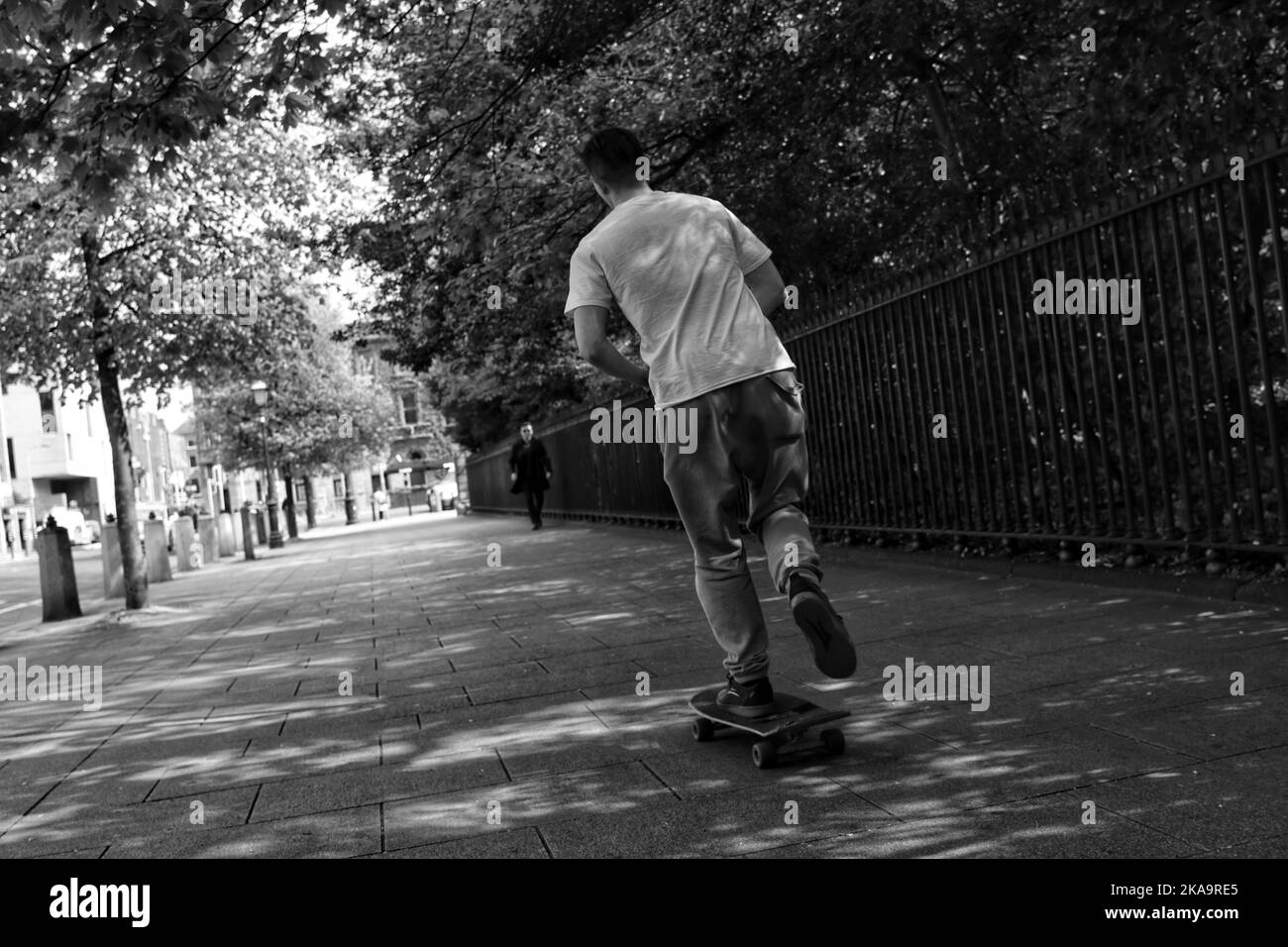 A greyscale back view of a young male skateboarding in the St. Stephen ...