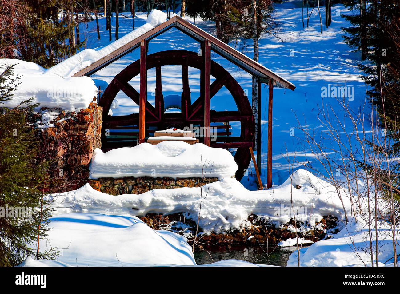 A small wooden structure with a round object and a roof in the snowy ...