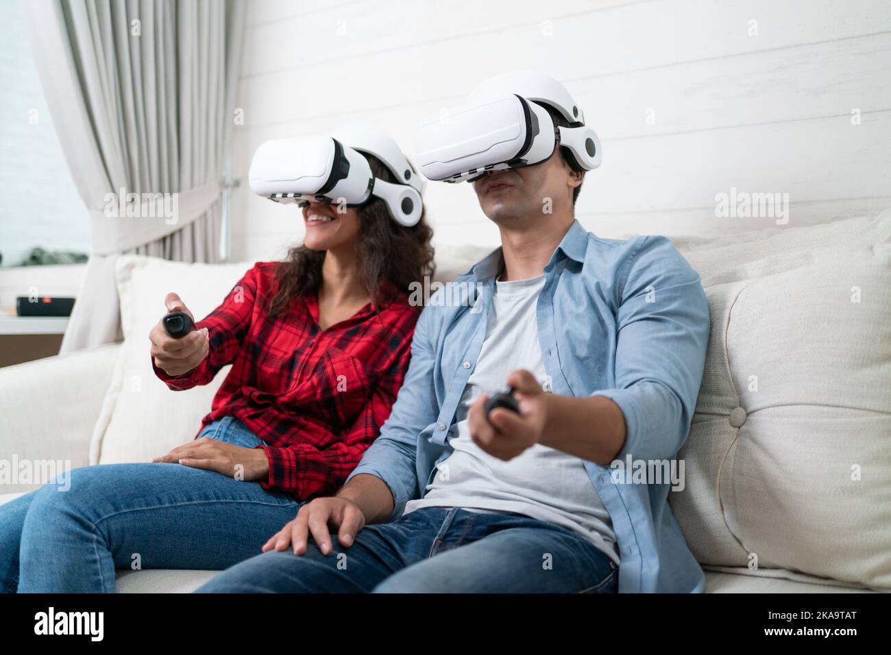 A happy couple in VR headsets holding controllers enjoying a virtual ...