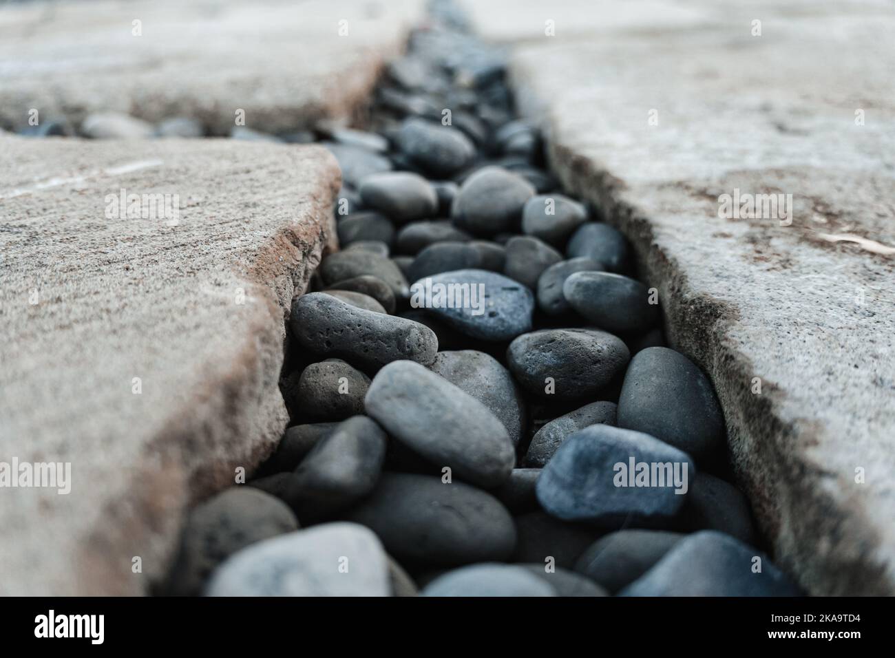 The stack of rocks in between concrete pavers Stock Photo - Alamy