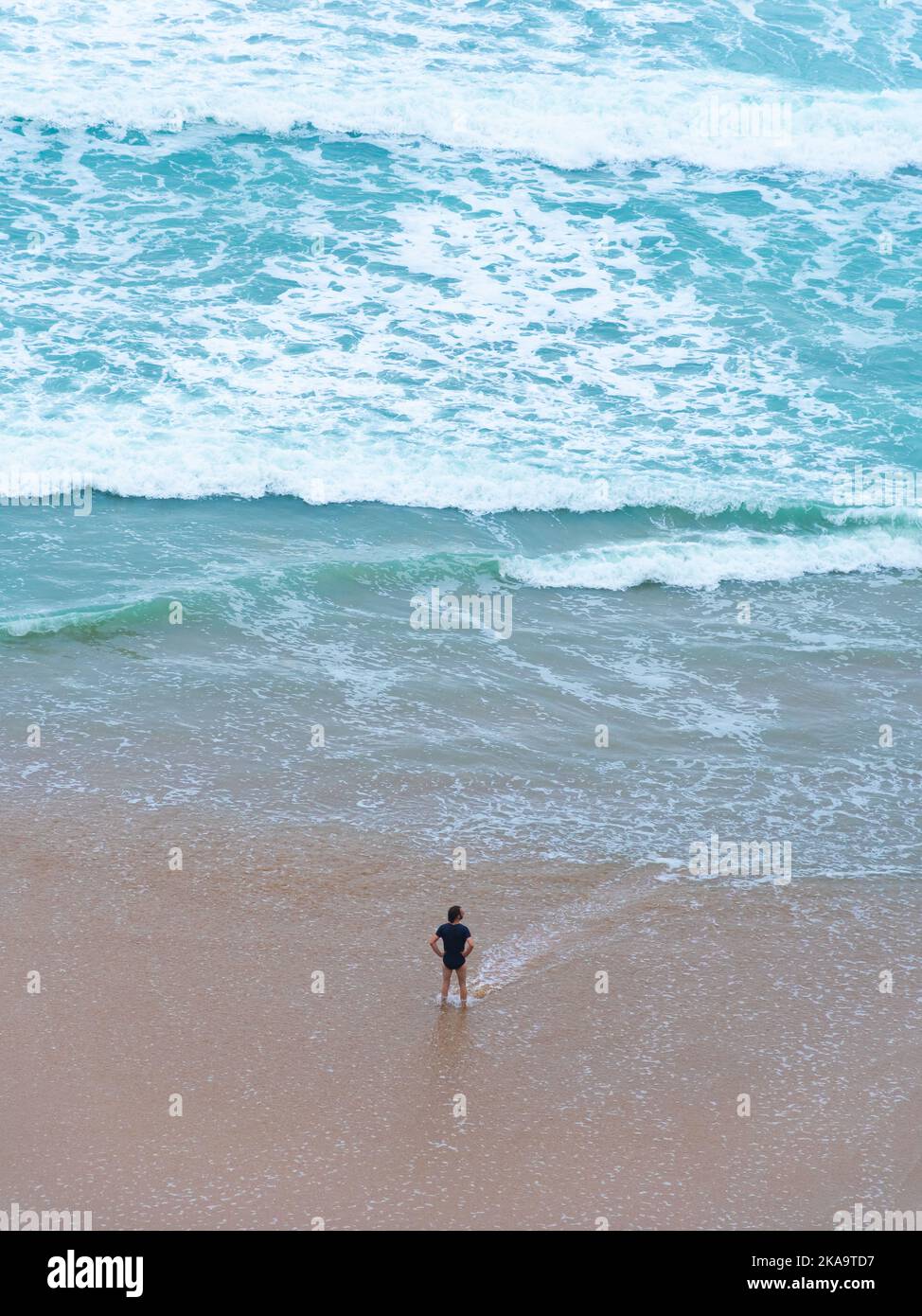 A vertical shot of a person standing on the sand of the beach against ...