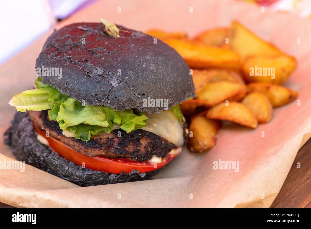 Fresh delicious grilled black burger on wooden table. Street food ...