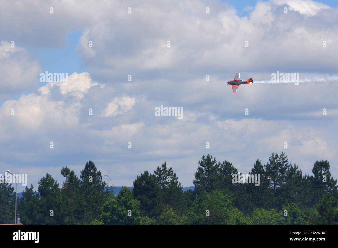 Small plane flying close to the ground at low altitude with smoke at ...
