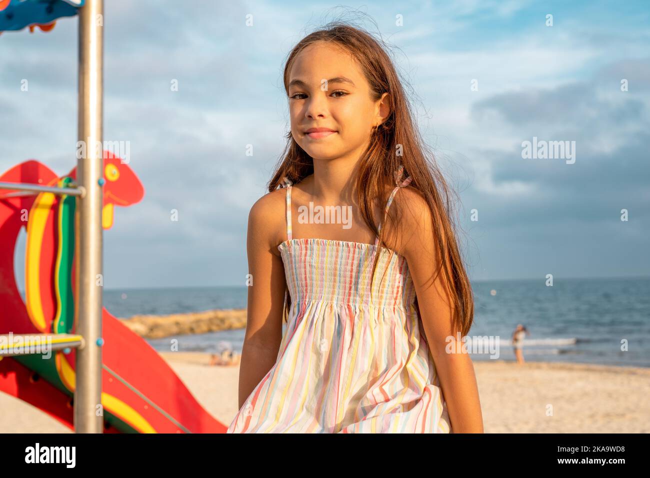 Little cute child girl in playground on the beach with smile on summer ...
