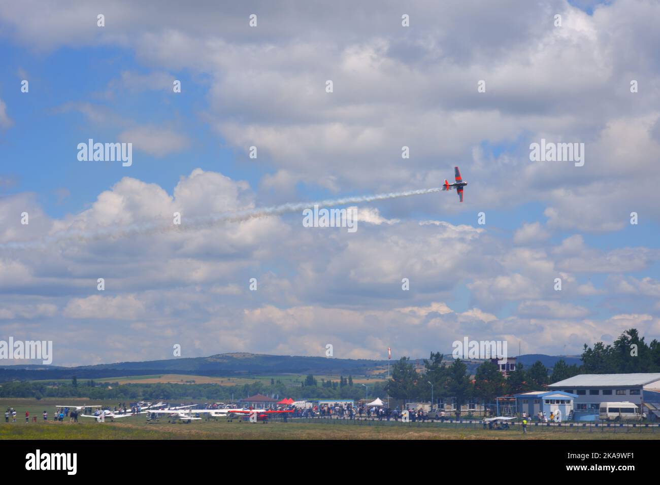 Small plane flying close to the ground at low altitude with smoke at ...