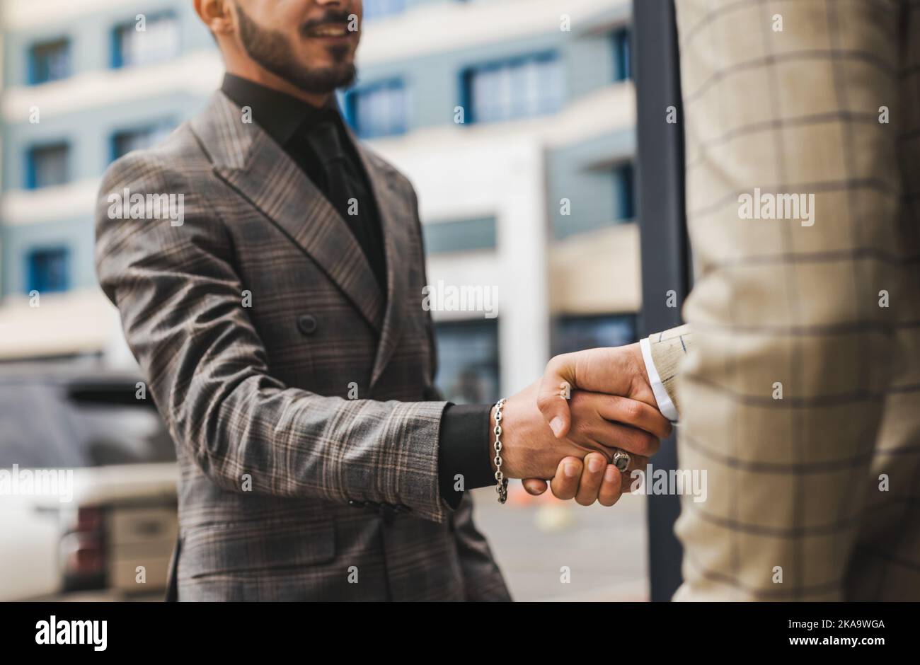 Business people outdoor meeting. Two men in suits hold out their hands ...