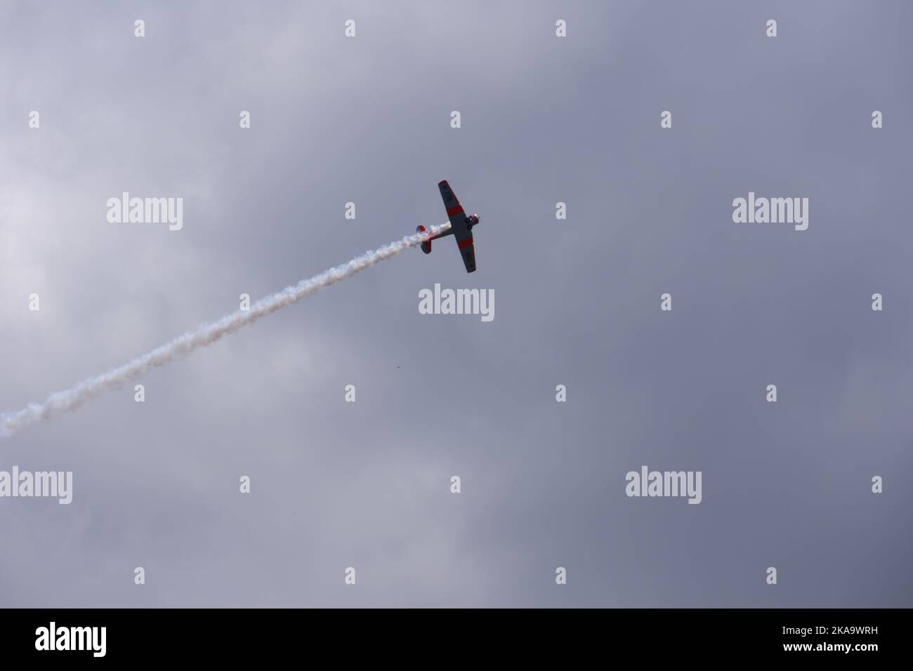 Plane flying within dark clouds with smoke on tail Stock Photo - Alamy