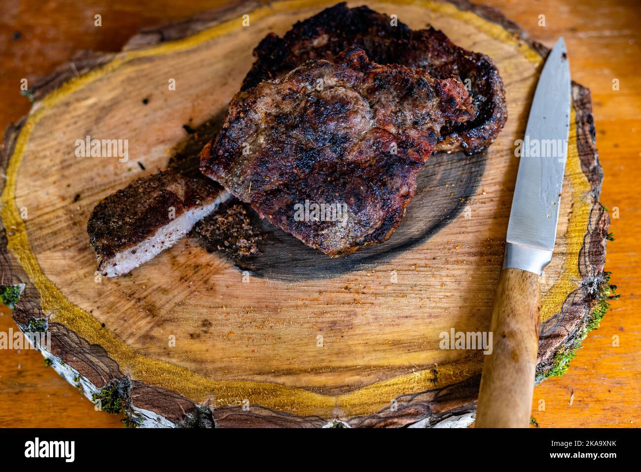 A piece of steak meat cooked on a wooden log Stock Photo - Alamy