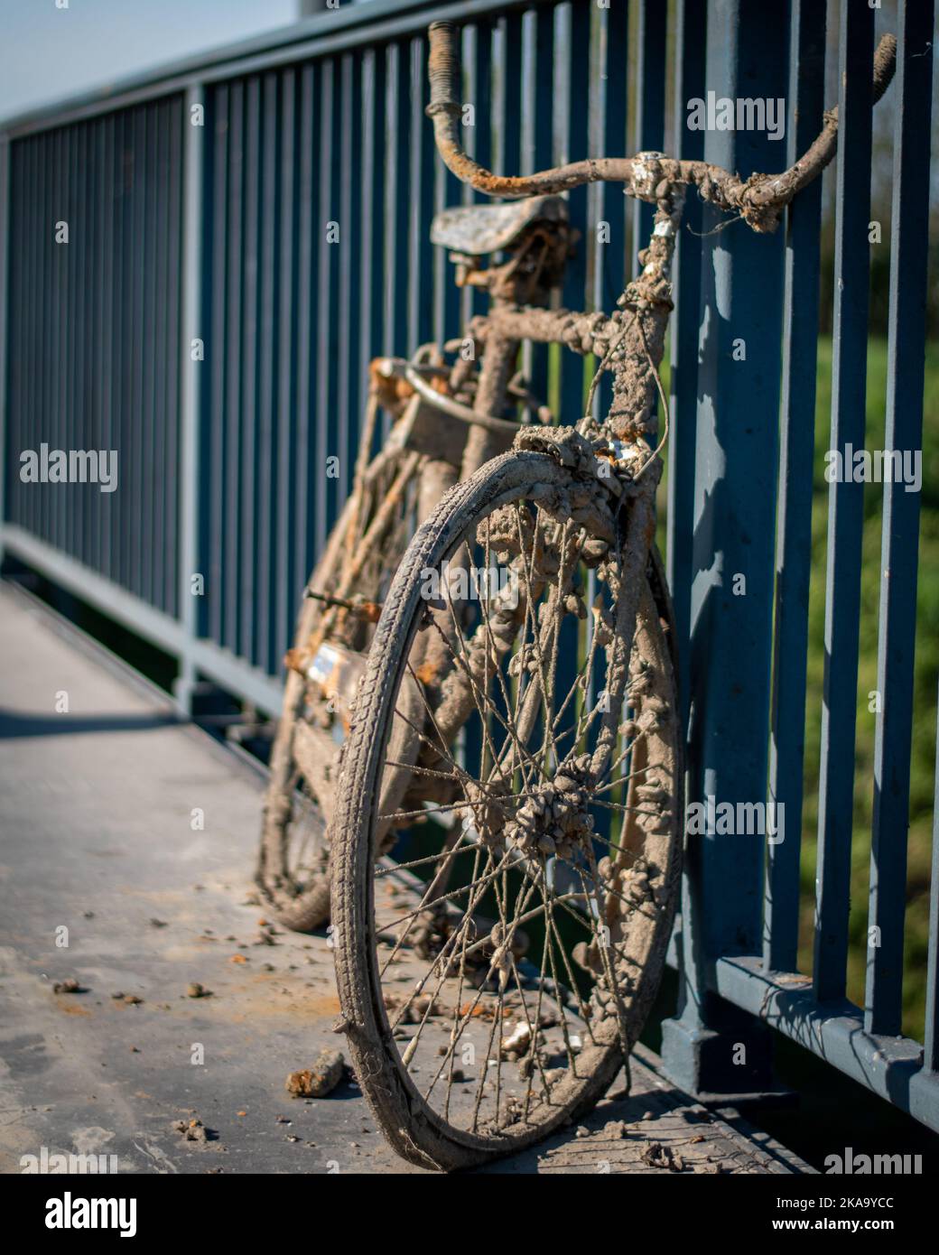 An old rusty bicycle parked in the street next to metal fences Stock ...