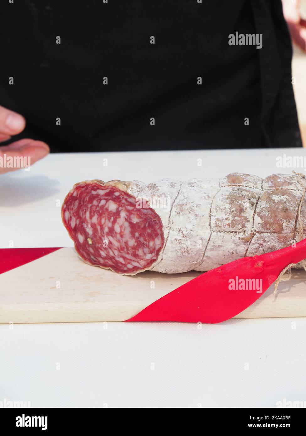 catering and waiting staff hand with knife slicing salami ham in a ...