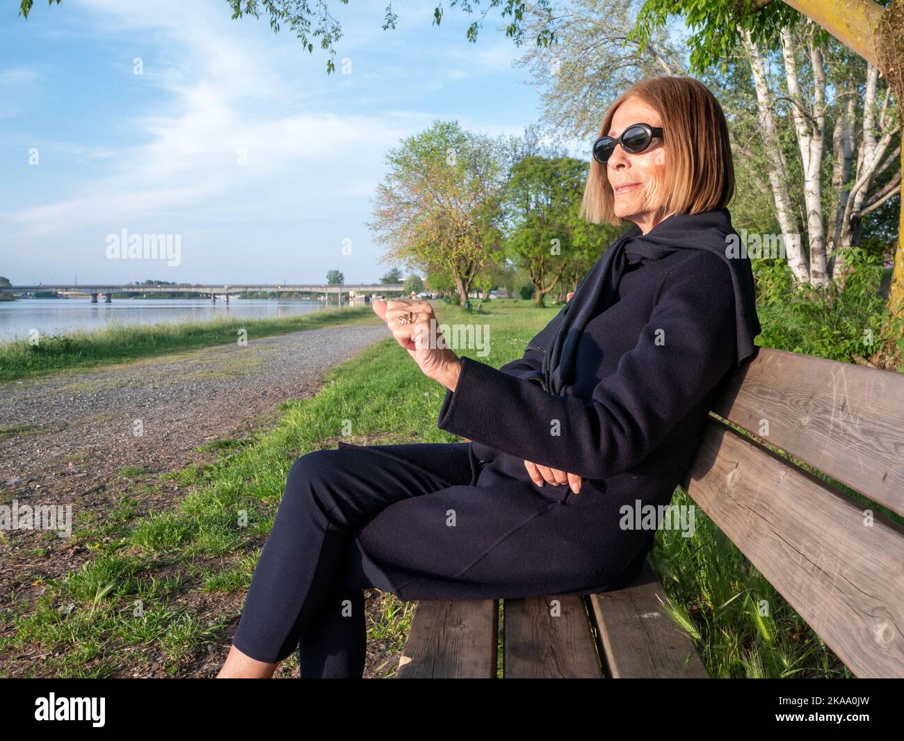 adult mature elegant caucasian woman sitting on a park bench with legs ...