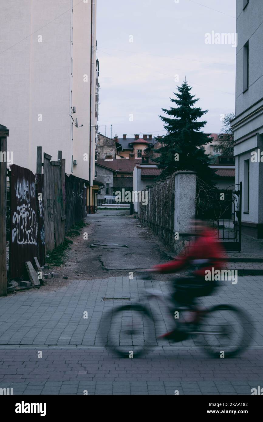 A narrow alley between commercial buildings with a male riding his ...