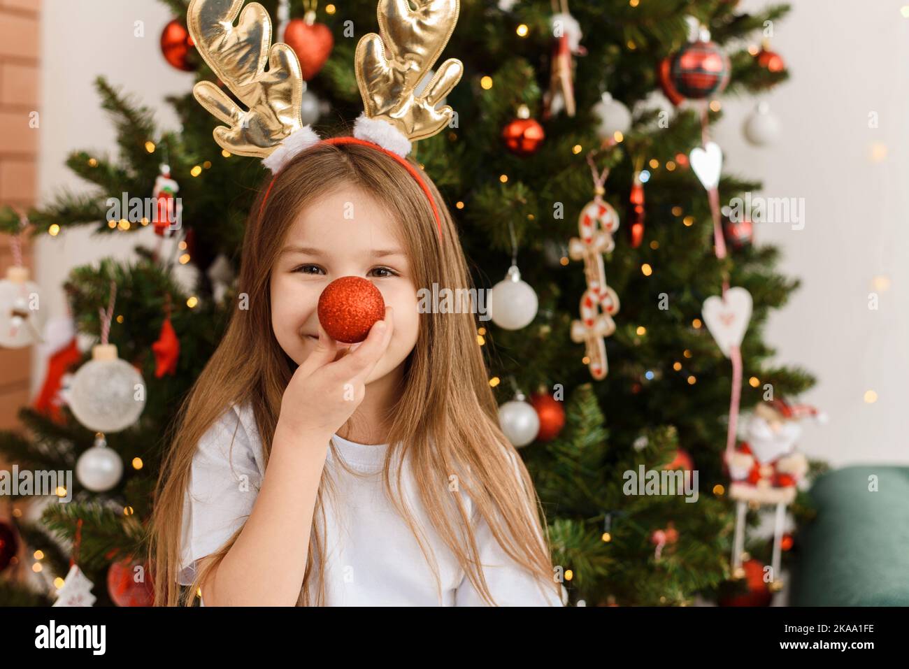 Portrait of a cute little girl wearing Rudolf horns holding a festive ...