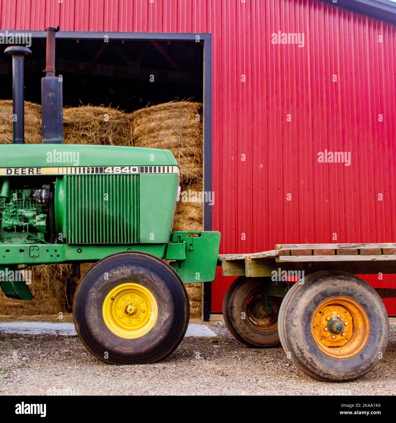 A close-up of a green John Deere tractor pulling a wooden platform in ...
