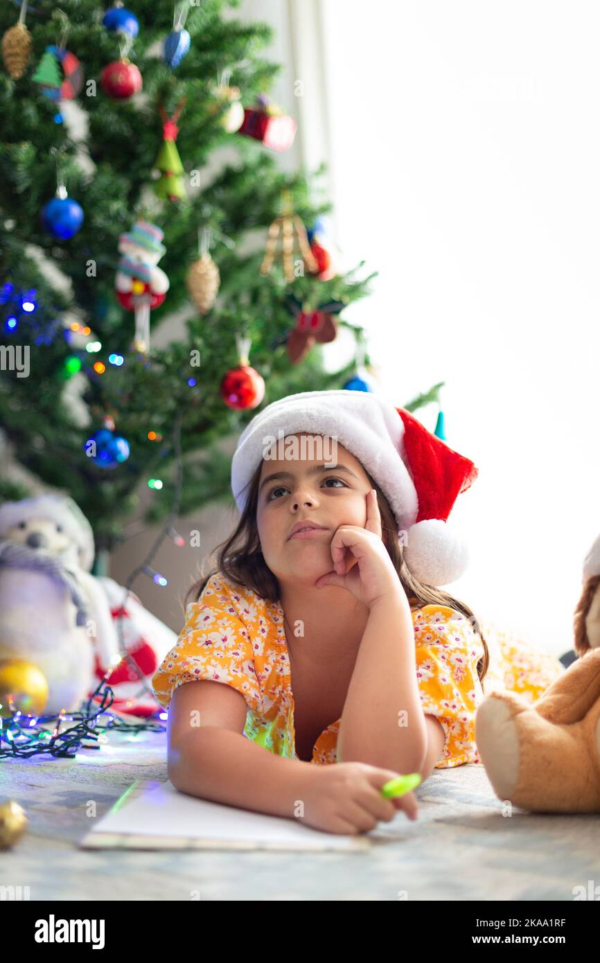 Caucasian little child thinking to write her wish list to Santa Claus ...