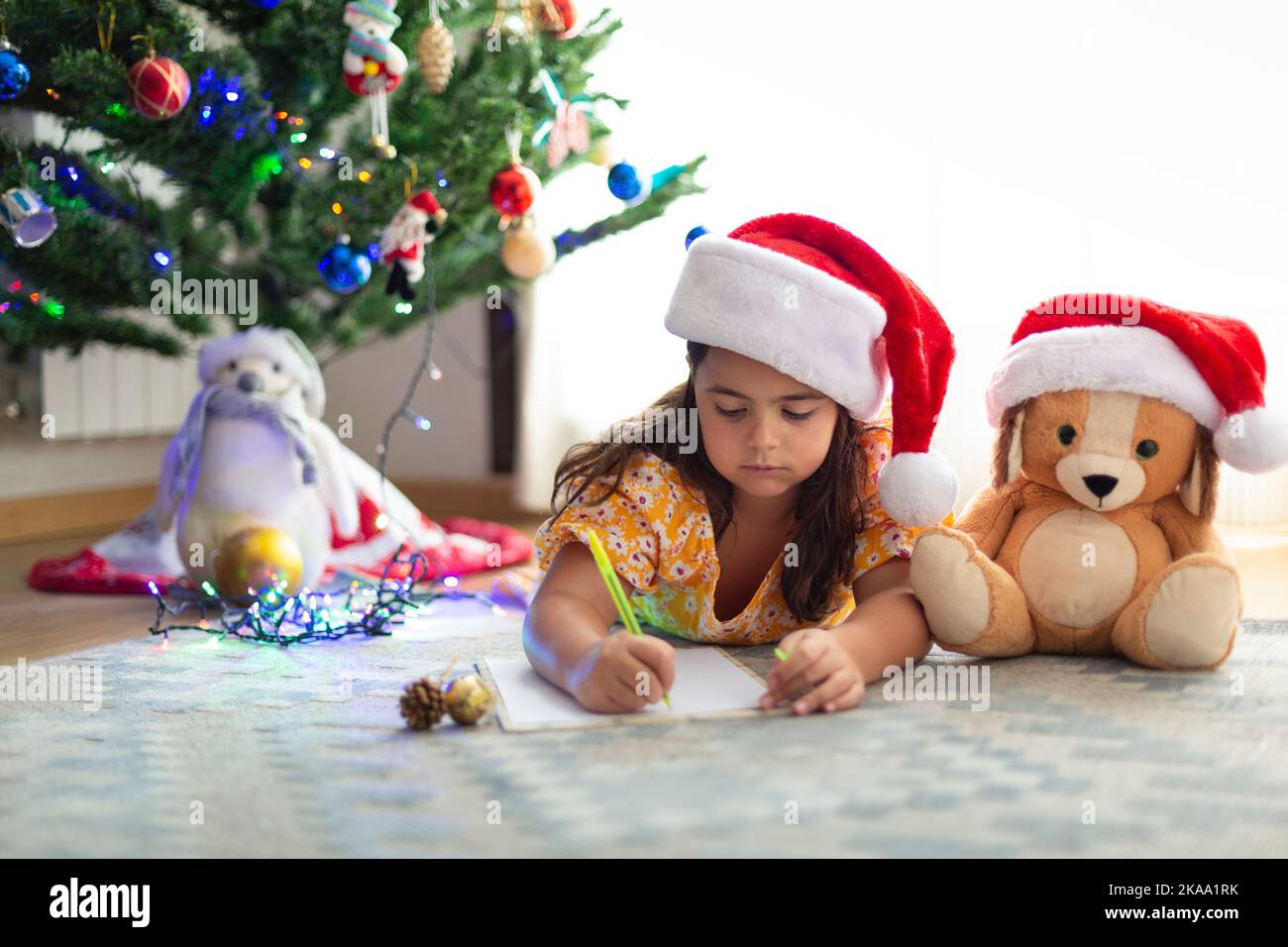Little girl writing wish list or letter to Santa Claus. She is in the ...