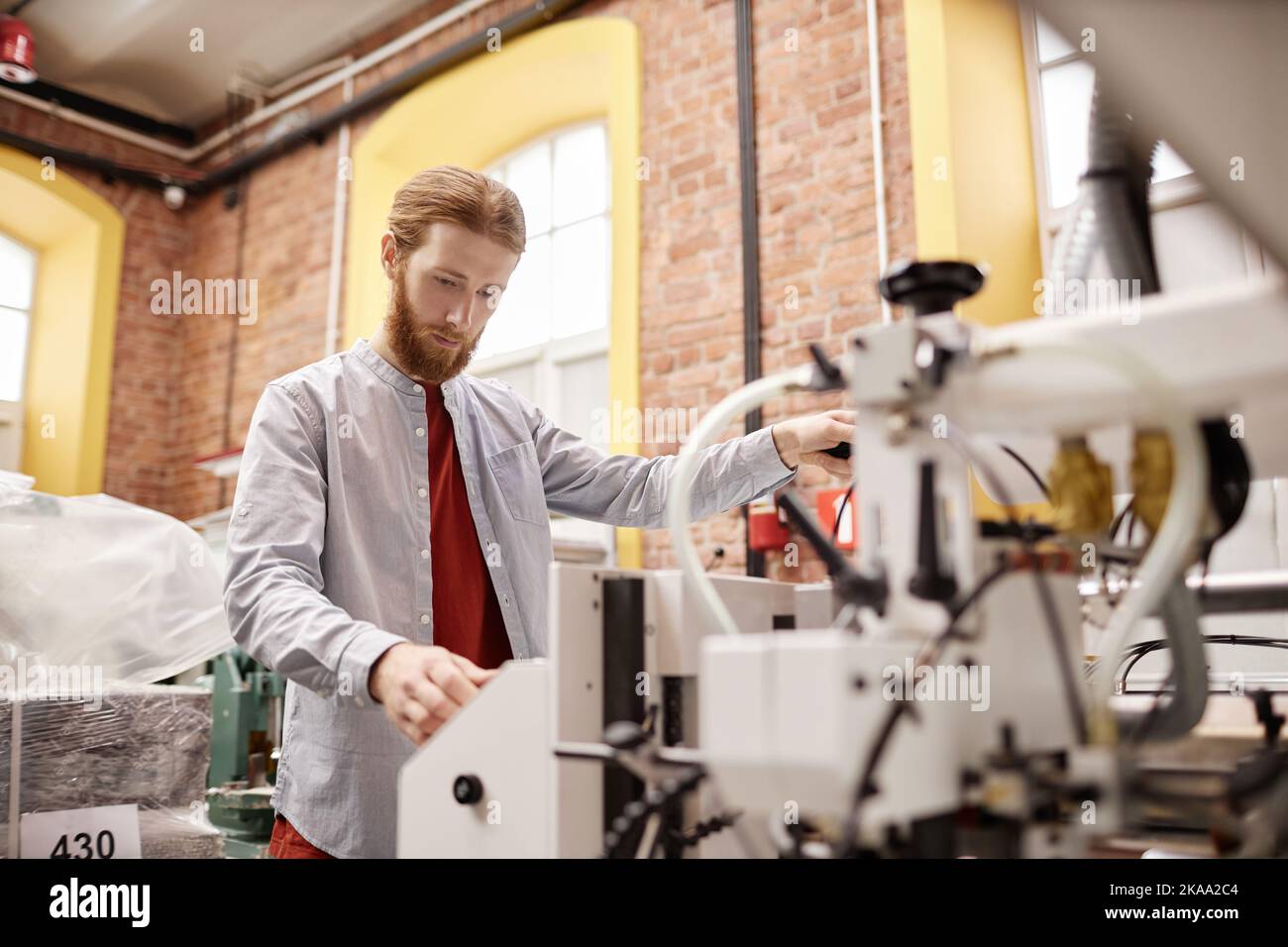 Portrait of young man working in print shop and operating industrial ...