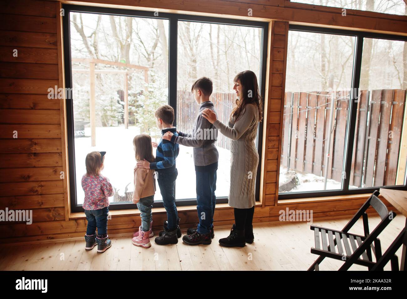 Mother and four kids in modern wooden house against large window Stock ...