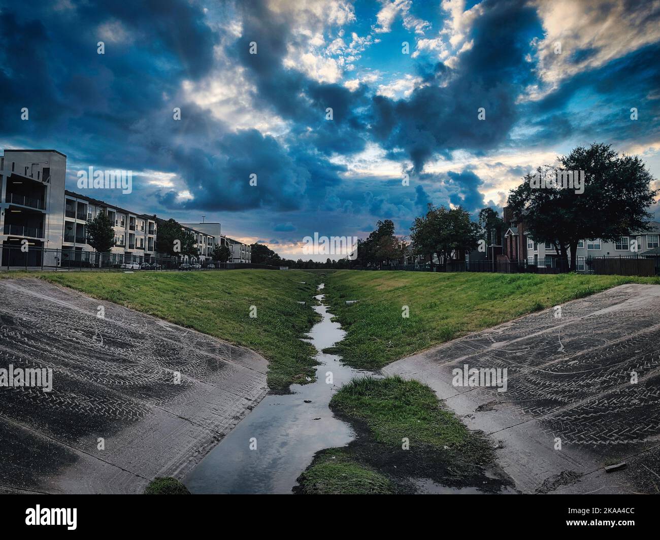The cloudy blue sky over the ditch and apartment buildings in spring ...