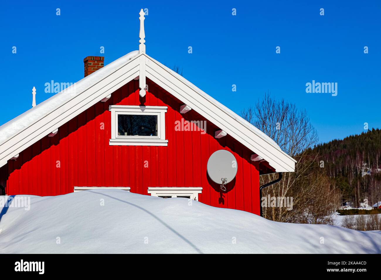 A beautiful red house covered with snow against blue sky background ...