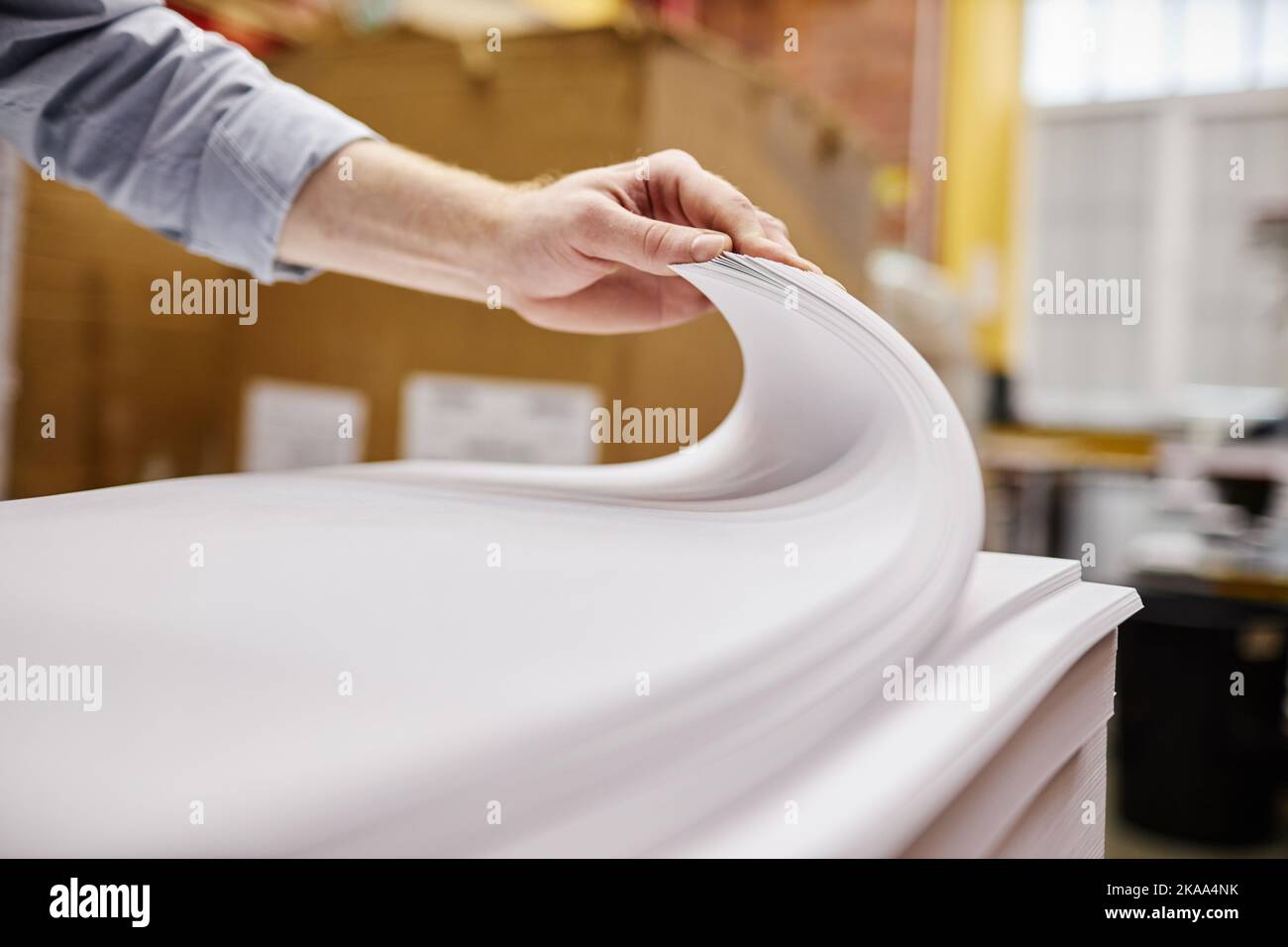 Close up of person checking quality of paper stack in printing shop ...