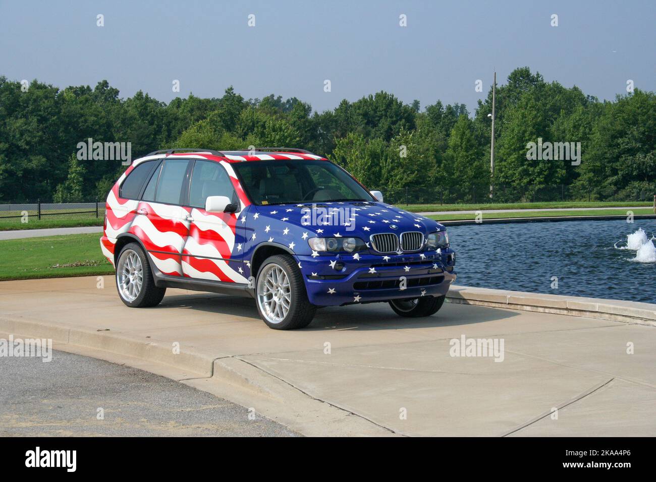 A 2006 BMW X5 car painted in the American Flag parked on a curb outside ...