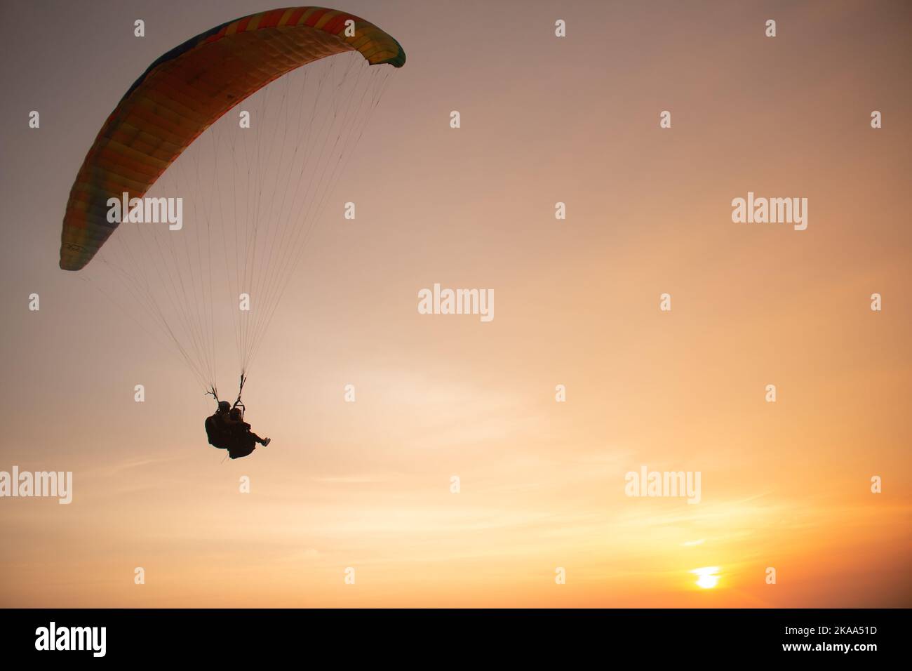 Tandem paragliding closeup over the ocean while golden sunset at ...